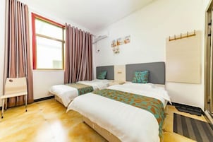 Quarto de hotel com duas camas, uma cadeira, uma janela com cortinas, um aparelho de ar condicionado e um cabideiro na parede.