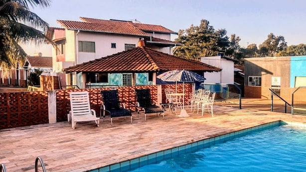 Piscina com espreguiçadeiras e área de estar coberta.