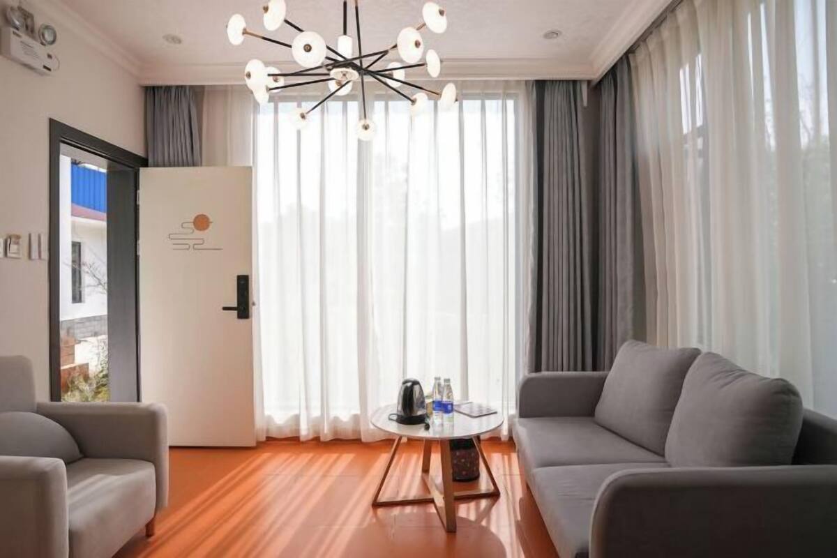 Uma sala de estar moderna com um sofá, uma mesa de centro, um candelabro e uma porta com um logotipo.
