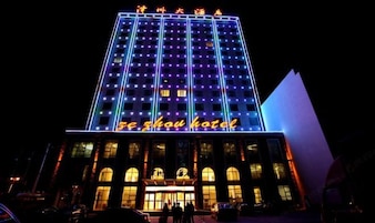 Um hotel com fachada moderna, iluminado por luzes coloridas, apresentando uma entrada e sinalização de destaque.