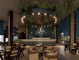 Um interior moderno com balcão de recepção, área de estar e plantas.