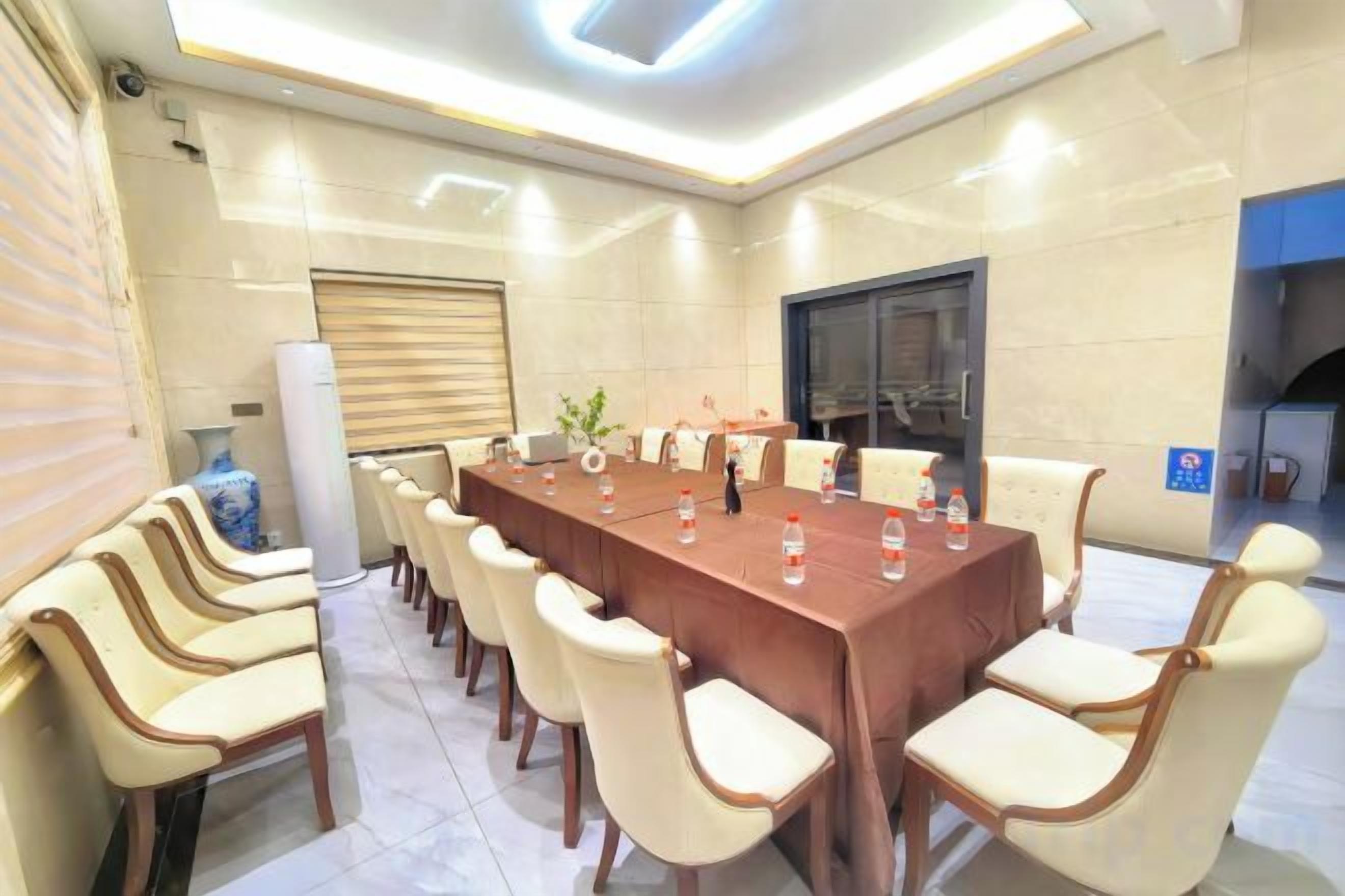 Uma sala de conferências com uma mesa comprida e cadeiras, uma janela grande e uma porta.