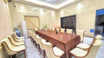 Uma sala de conferências com uma mesa comprida e cadeiras, uma janela grande e uma porta.