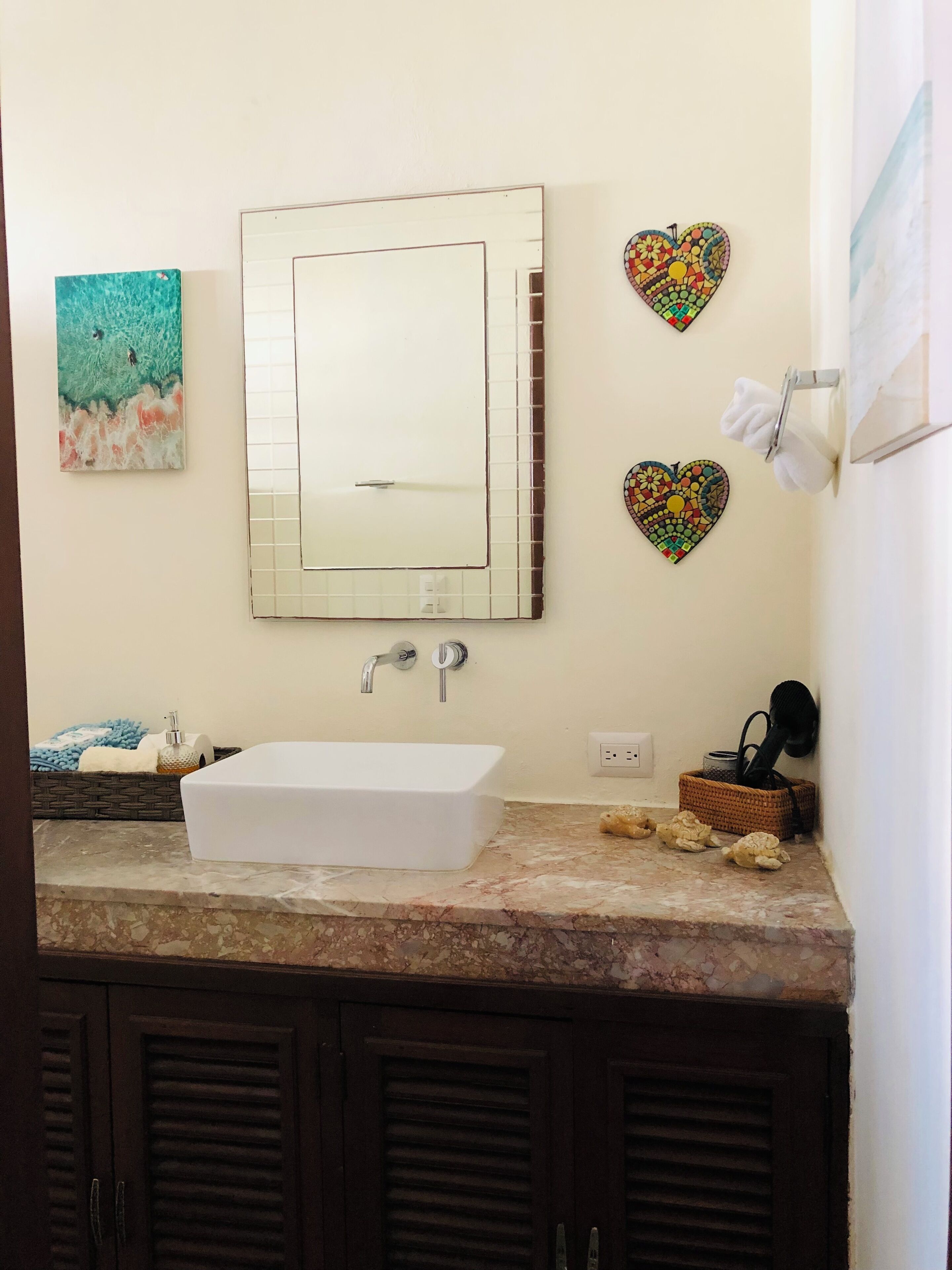Um banheiro com pia branca, espelho e azulejos decorativos em formato de coração na parede.