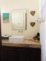 Um banheiro com pia branca, espelho e azulejos decorativos em formato de coração na parede.