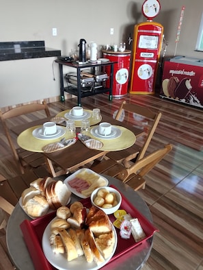 Mesa de jantar com pratos de comida, copos e bandeja com pão e doces.