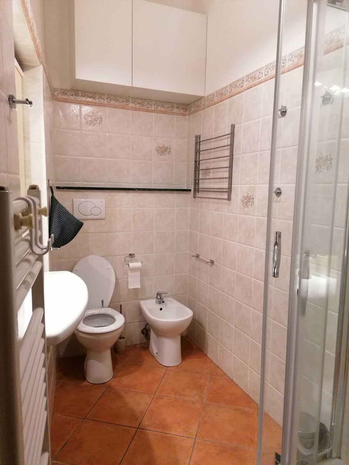 Casa de banho com sanita, bidé e cabine de duche em vidro.