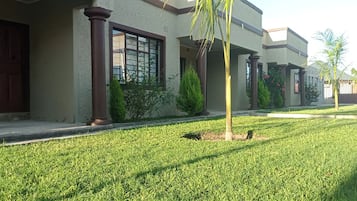 Um edifício residencial com um gramado bem cuidado, uma porta e uma janela.