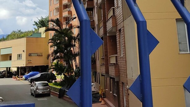 Um edifício residencial alto com várias varandas e fachada amarela.