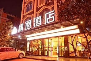 Um hotel com placa, entrada coberta e um carro estacionado em frente.