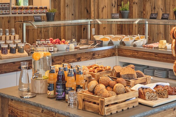 Uma área de buffet com diversos alimentos, incluindo pão, frutas e acompanhamentos.