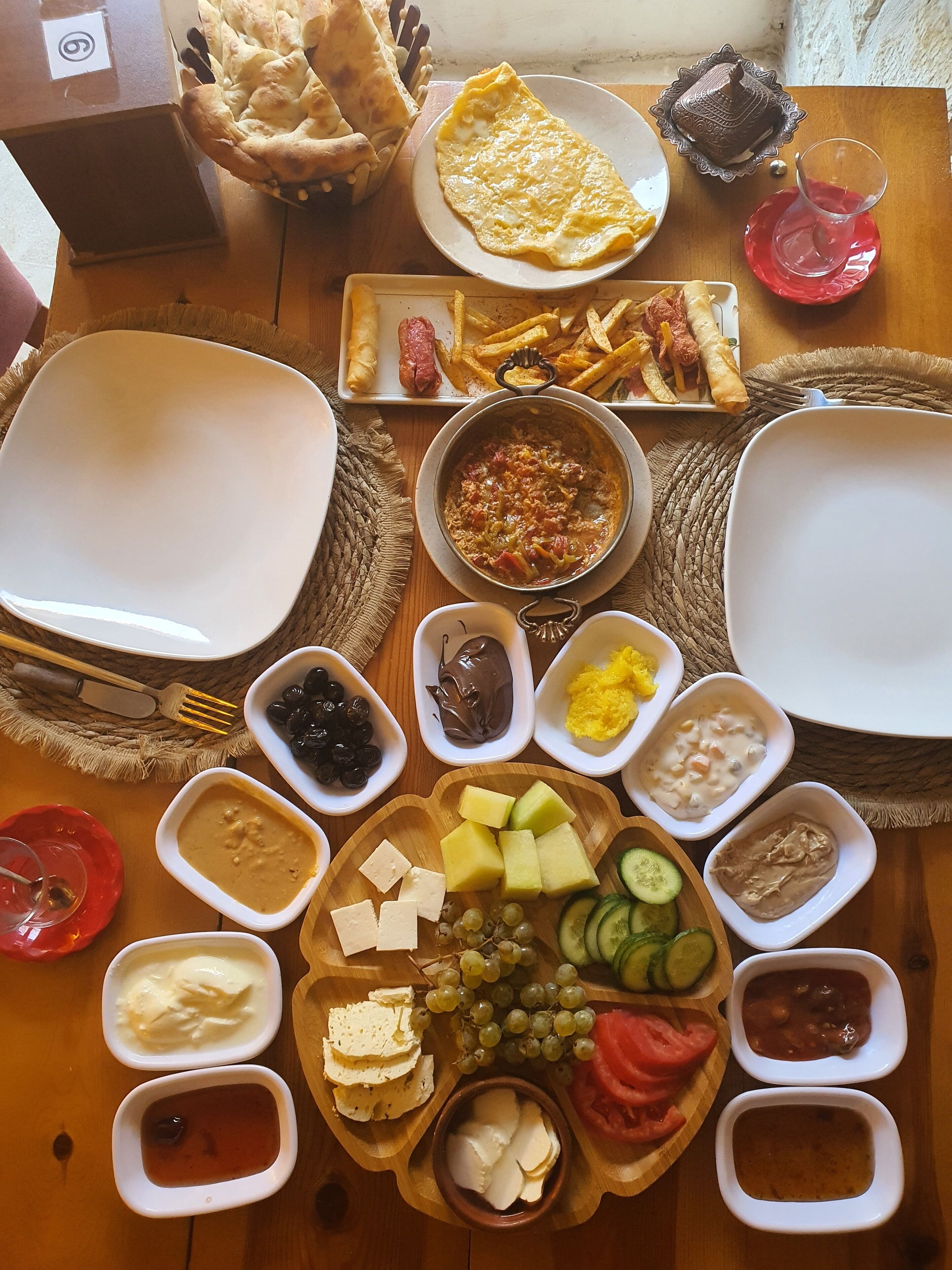 Uma mesa posta com diversos alimentos, incluindo queijo, frutas e acompanhamentos.