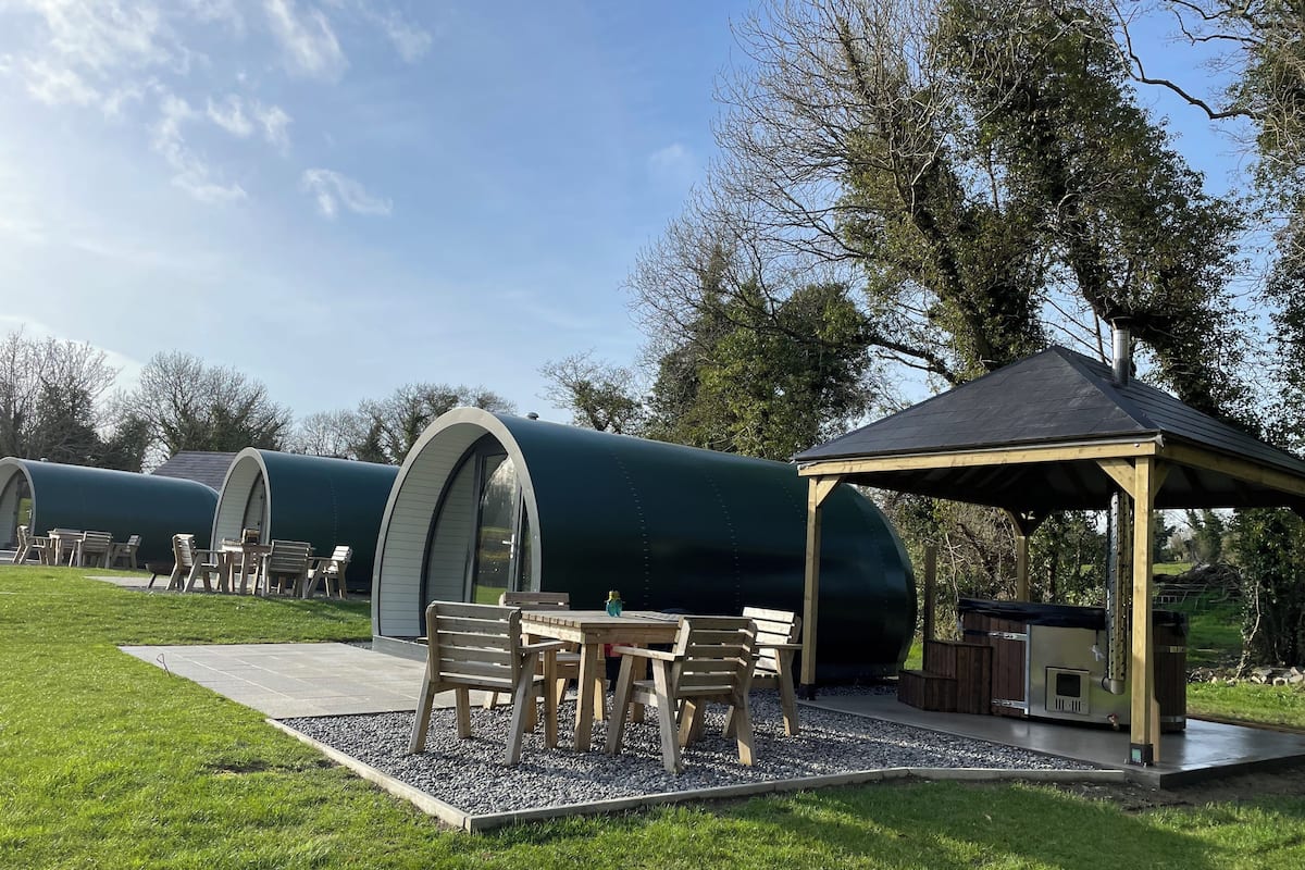 Uma série de cabanas em forma de cúpula, com áreas de estar ao ar livre, um gazebo e um gramado bem cuidado.