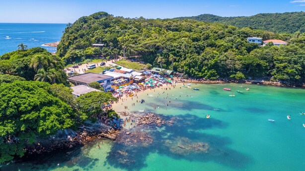 Um resort à beira-mar com praia, águas cristalinas e vegetação exuberante.