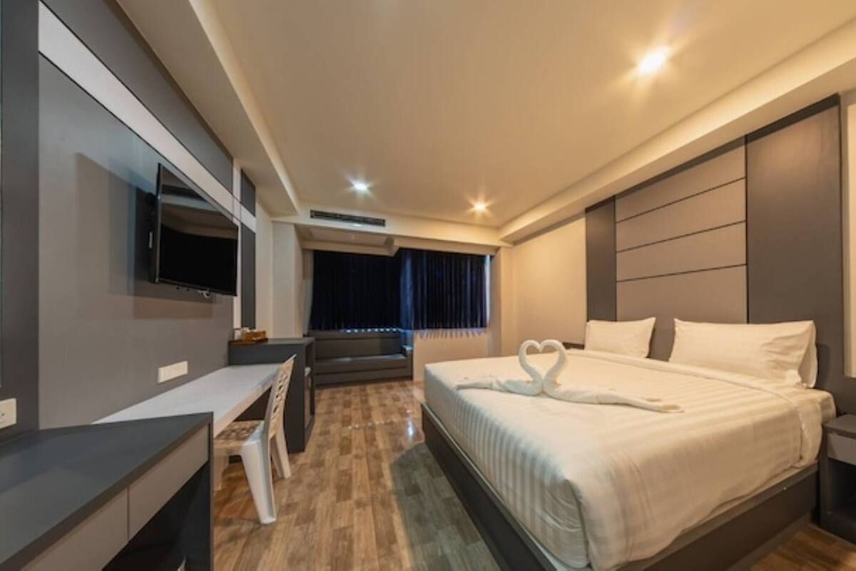 Quarto de hotel moderno com uma cama grande, uma escrivaninha e uma televisão.