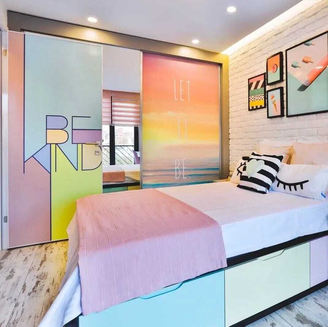 Quarto moderno com cama, roupeiro deslizado e parede com obras de arte motivacionais.