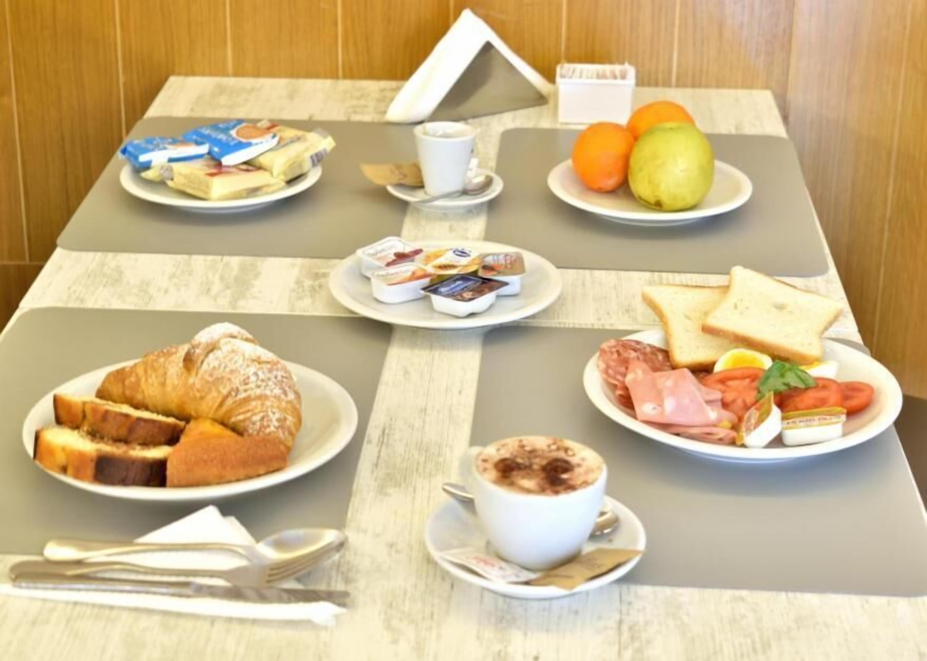 Uma mesa de café da manhã com pratos de comida, uma xícara de café e um guardanapo.