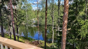 Um deck de madeira com vista para um lago calmo, rodeado por uma floresta densa.
