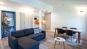 Uma sala de estar moderna com um sofá seccional, uma mesa de jantar com cadeiras e vista para uma área de cozinha.
