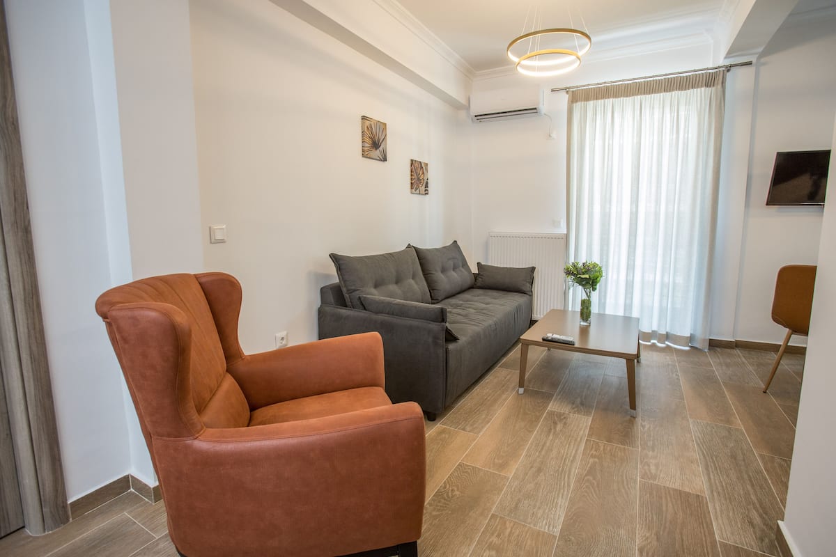 Uma sala de estar moderna com um sofá, poltrona e uma pequena mesa.