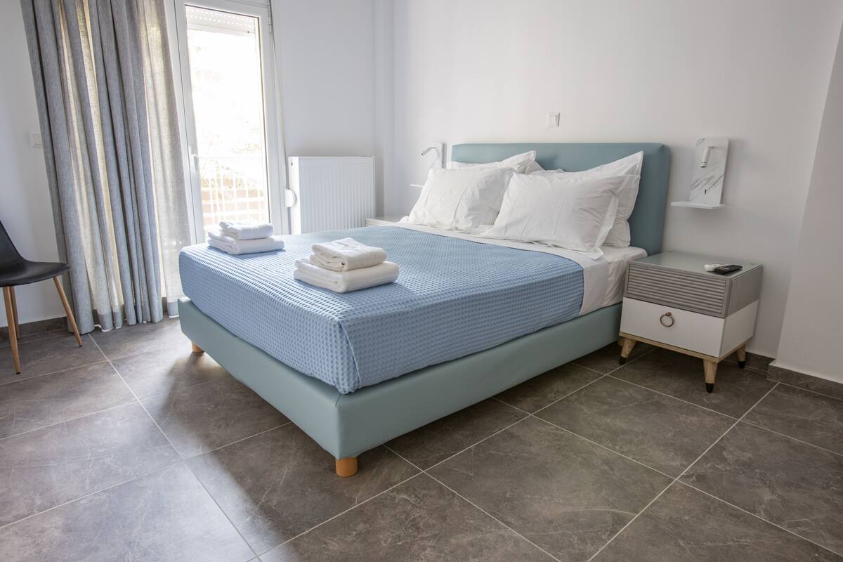 Quarto moderno com cama, mesa de cabeceira e uma cadeira.