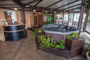 Uma área de spa com hidromassagem, balcão de recepção e bancos de madeira.