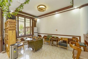 Um quarto com estante de madeira, sofá, mesa de jantar e cadeiras.