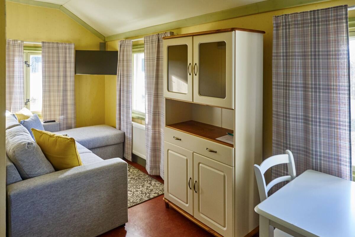 Quarto compacto com sofá, mesa pequena e armário.