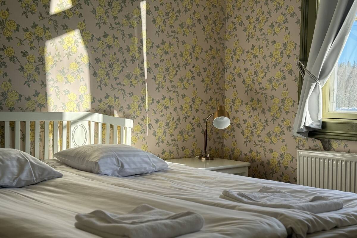 Cama bem arrumada com almofadas, abajur e radiador.