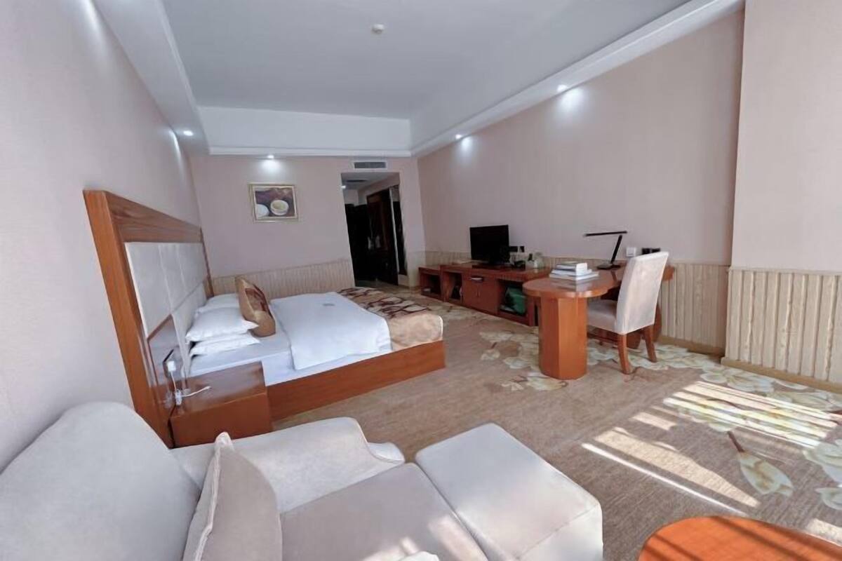 Quarto de hotel com cama, sofá, escrivaninha e cadeira.