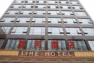 Edifício de hotel com fachada moderna, grandes janelas e uma placa indicando o nome 'LIHE HOTEL'.