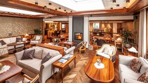 Uma sala de estar ampla com lareira, piso de madeira e diversas opções de assentos, incluindo sofás e poltronas.