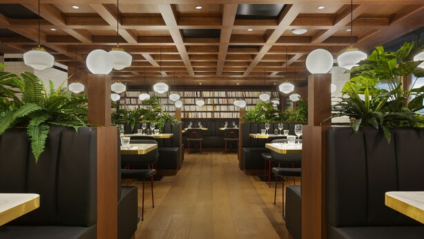 Restaurante com vigas de madeira no teto, assentos estofados pretos e luminárias esféricas penduradas.