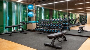 Uma academia com equipamentos de exercícios, paredes espelhadas e teto de madeira.