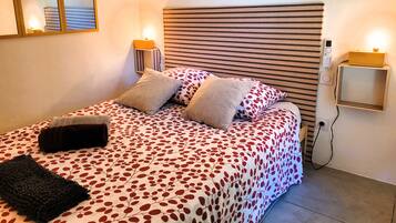 Cama bem arrumada com colcha estampada, dois travesseiros e um cobertor dobrado.