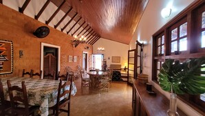Uma área de refeições com parede de tijolos, vigas de madeira no teto e uma grande janela.