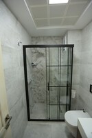 Casa de banho com cabine de duche em vidro, sanita e lavatório.