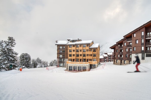 Um moderno edifício de estância de esqui com vários andares, teleféricos e paisagem coberta de neve.
