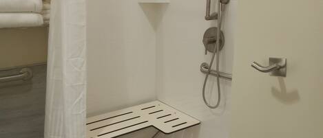 Área de chuveiro com chuveiro branco, chuveiro manual e painel de controle.