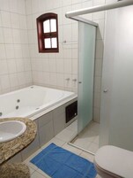 Uma casa de banho com banheira, lavatório, sanita e cabine de duche.