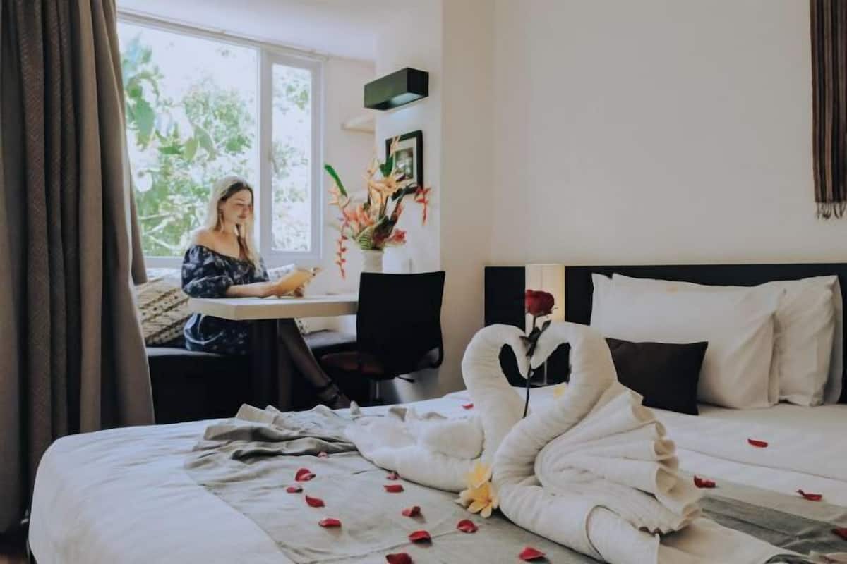 Quarto de hotel com uma cama, uma escrivaninha e uma janela.
