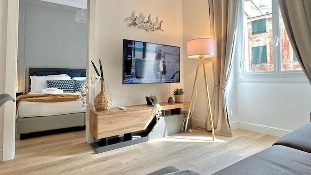 Quarto de hotel moderno com uma cama, uma TV, uma escrivaninha e um abajur.