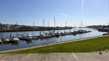 Marina com barcos atracados, área gramada e céu claro.
