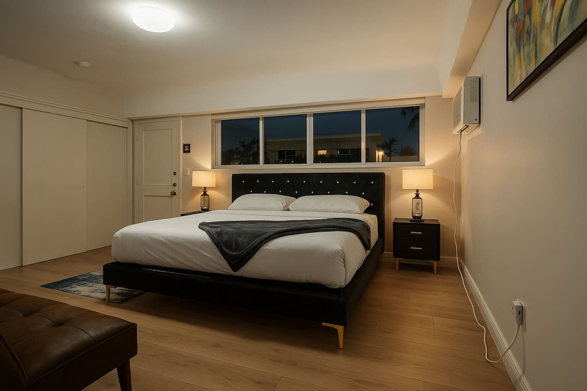 Quarto com cama, mesas de cabeceira, luminária e janela.