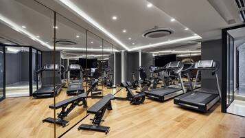 Academia moderna com diversos equipamentos de exercício, incluindo esteiras e máquinas de musculação, e piso de madeira.