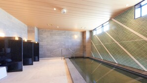 Uma área interna de piscina moderna, com uma parede de vidro, uma parede de pedra e um teto de madeira.