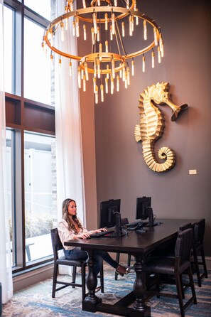 Uma sala de conferências com uma mesa grande, cadeiras, um lustre e uma decoração de parede com um cavalo-marinho.