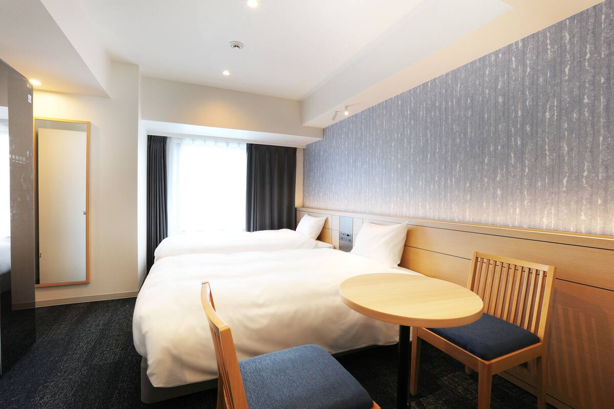Quarto de hotel com uma cama grande, uma mesa redonda e uma cadeira.