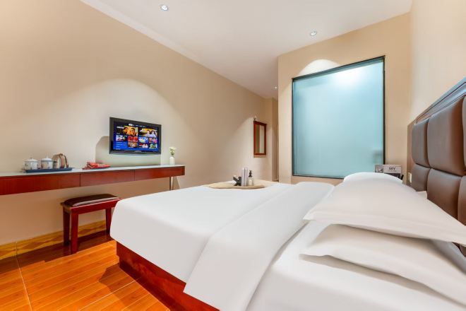 Quarto de hotel com uma cama, televisão, escrivaninha e janela.