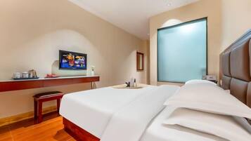 Quarto de hotel com uma cama, televisão, escrivaninha e janela.